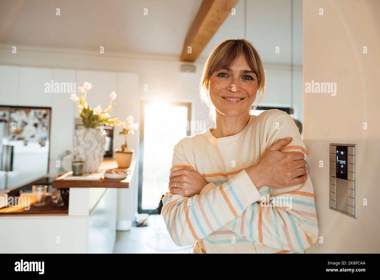 Happy woman hugging self near thermostat on wall at home Stock Photo ...