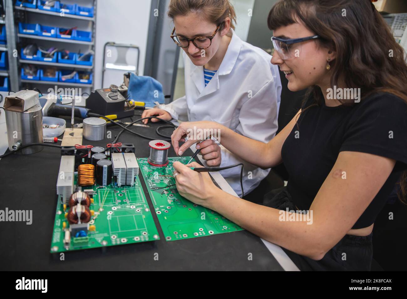 Engineers soldering circuit board together in electronics industry ...