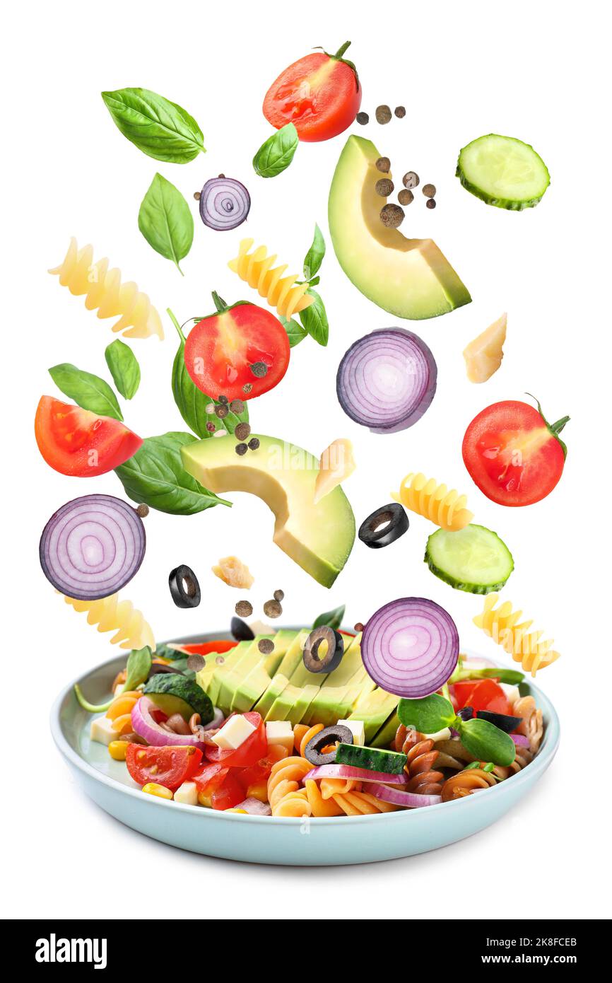 Plate with delicious pasta salad and falling ingredients on white ...