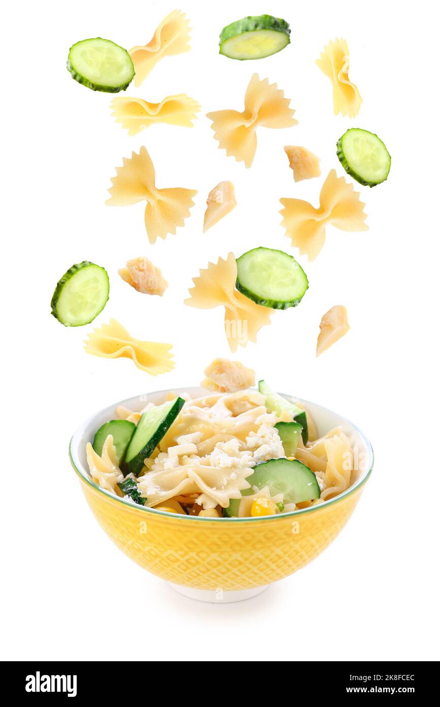 Bowl with tasty pasta salad and falling ingredients on white background ...