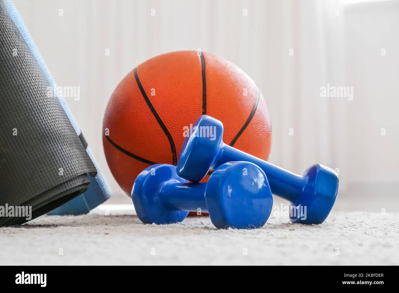 Dumbbells and ball on floor in room Stock Photo - Alamy