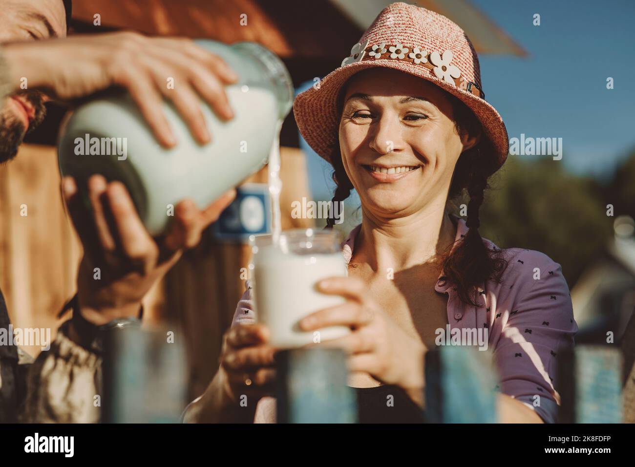 Happy girlfriend holding glass jar with boyfriend pouring milk Stock ...