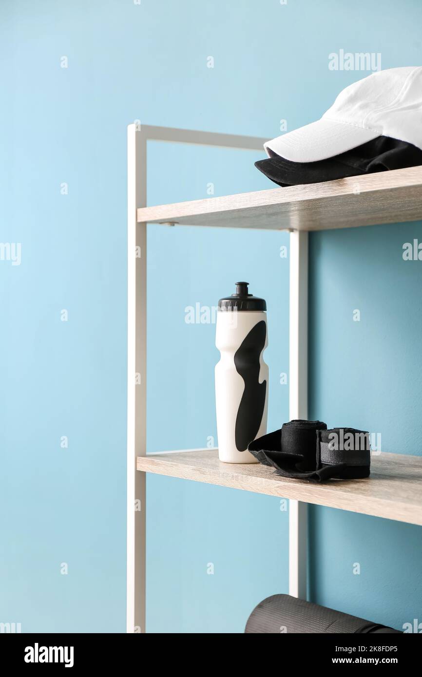 Sport equipment and bottle of water on shelf unit near color wall Stock ...