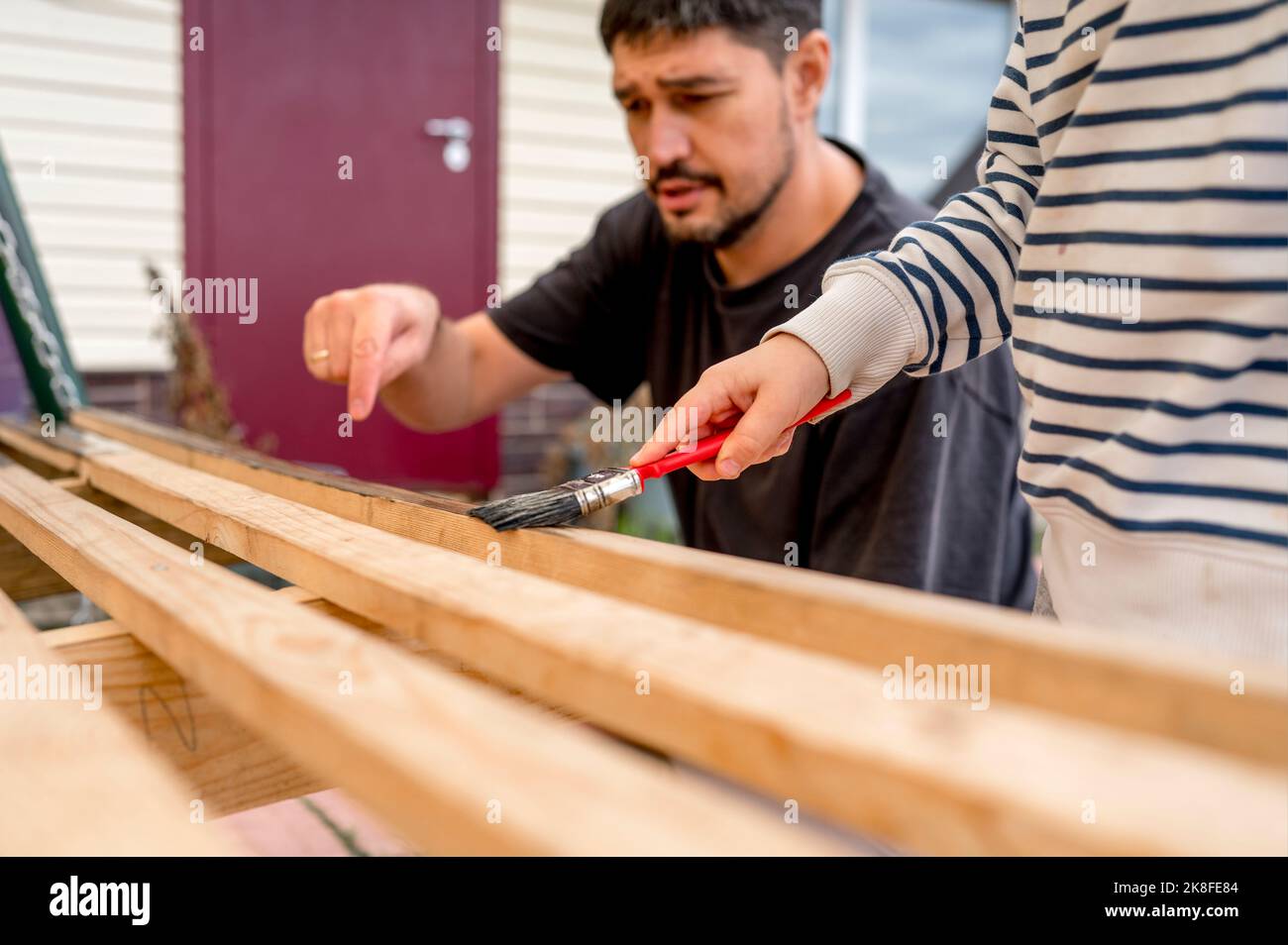 Man guiding son to paint wooden swing Stock Photo - Alamy