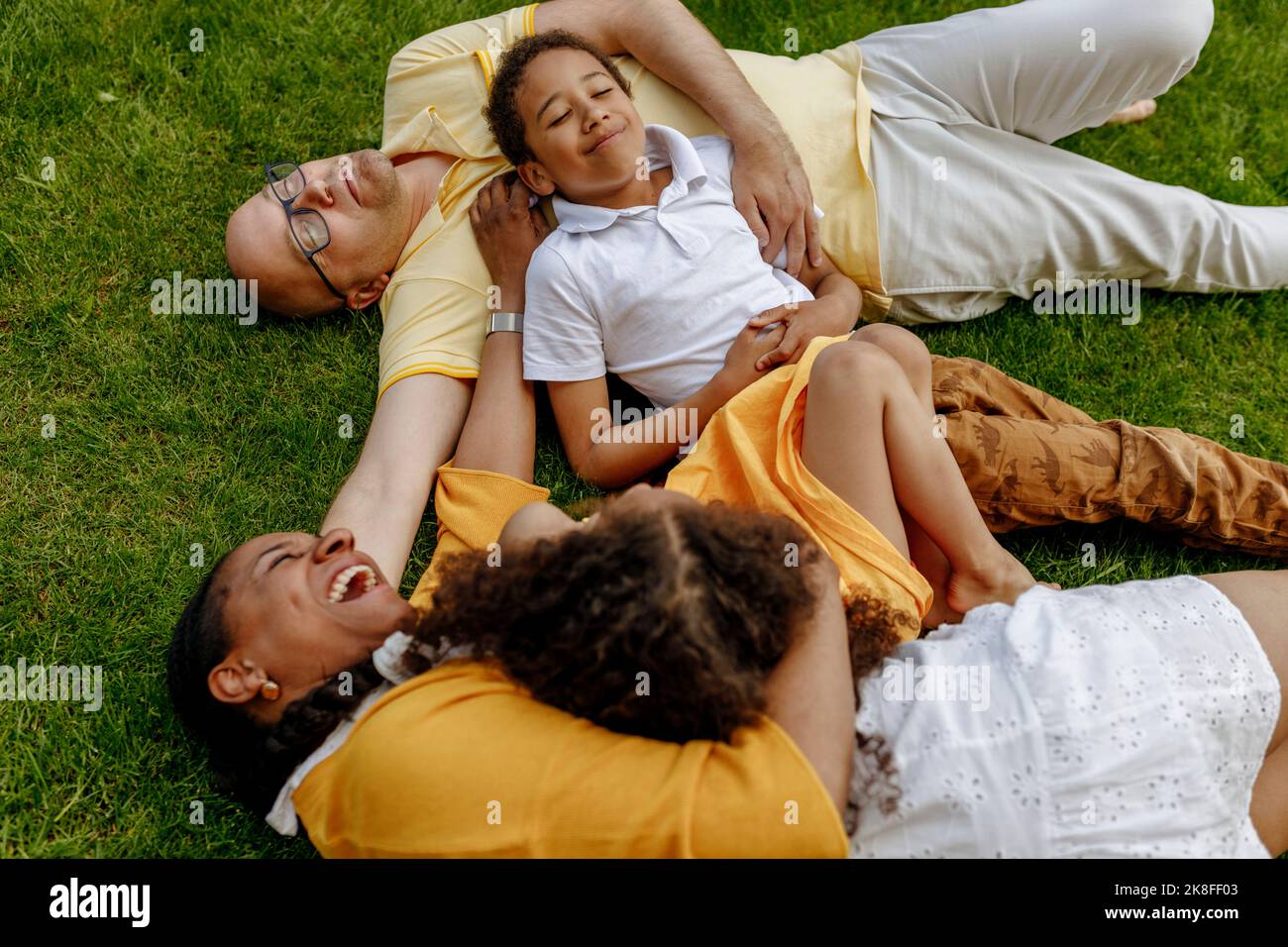 Happy woman with man and children lying on grass Stock Photo - Alamy