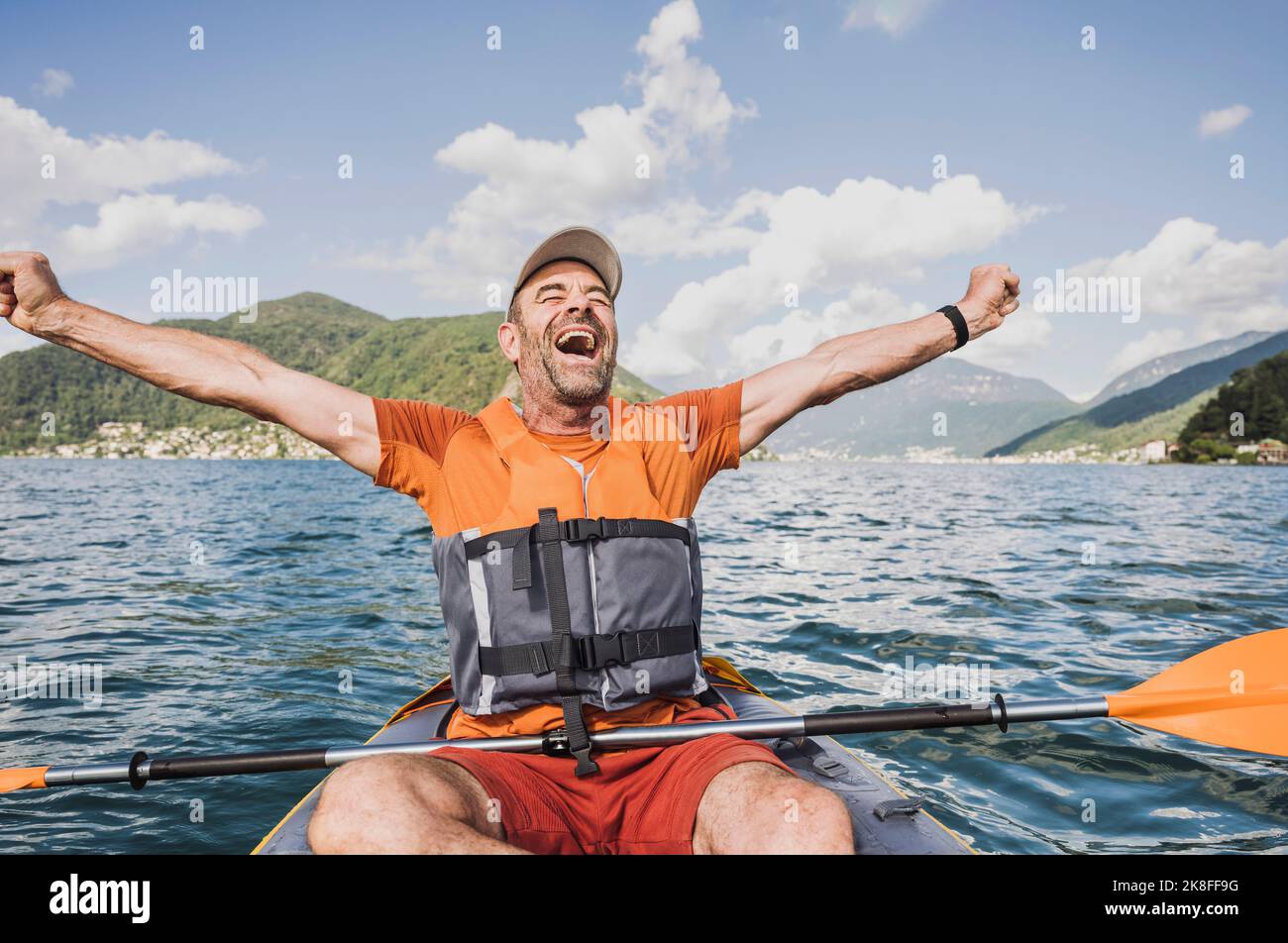Excited mature man screaming with arms outstretched on lake Stock Photo ...