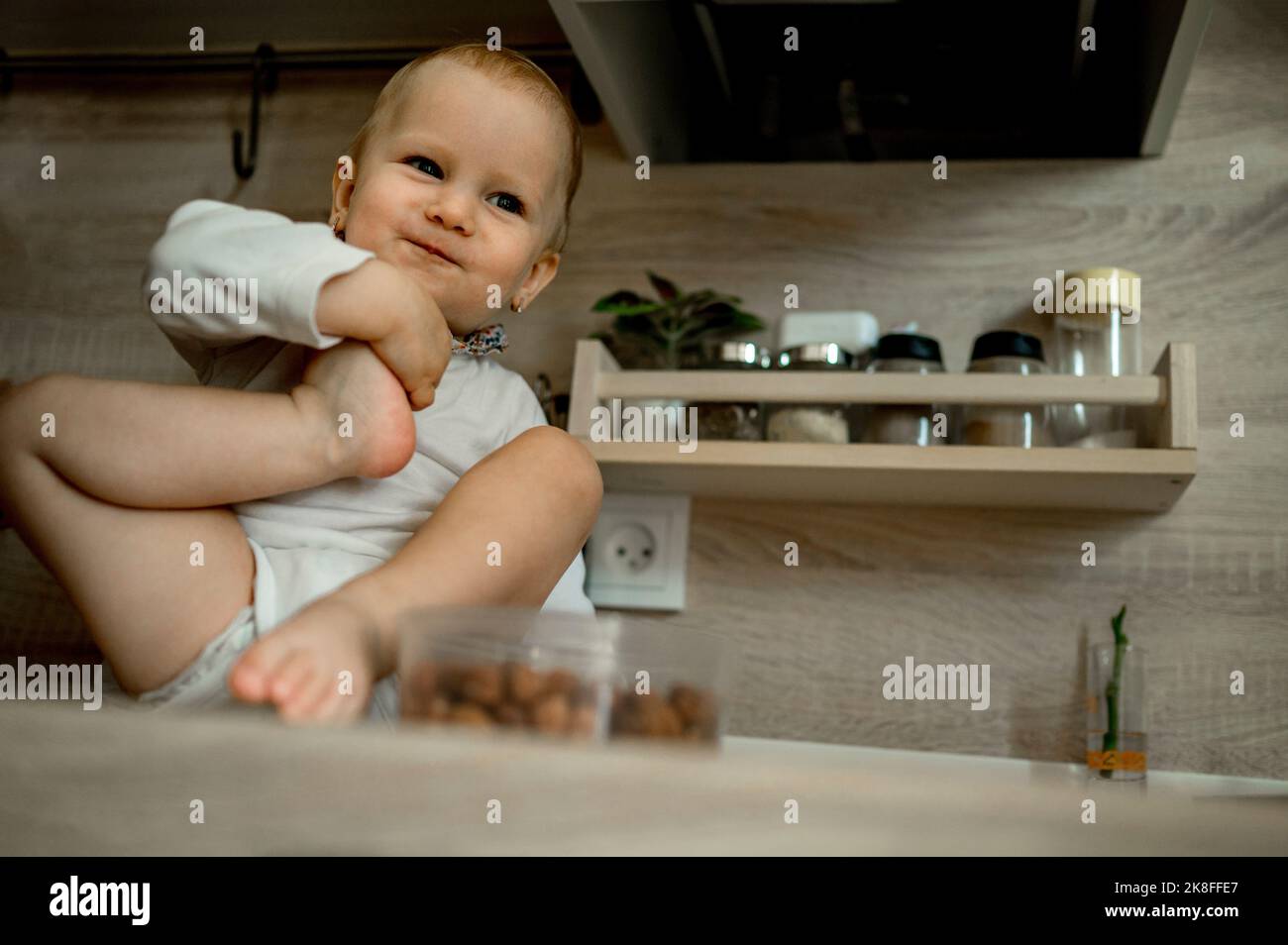 Cute baby girl sitting on kitchen counter at home Stock Photo - Alamy