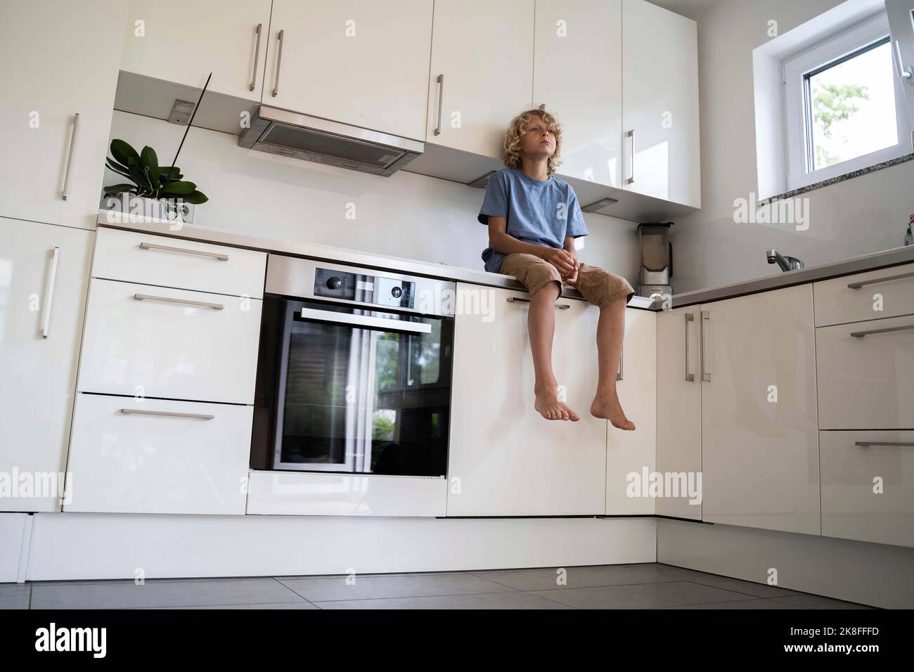 Boy sitting on kitchen counter at home Stock Photo - Alamy