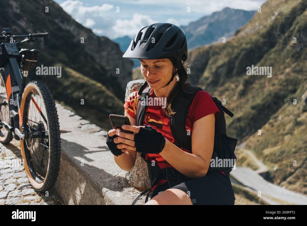 Cyclist wearing helmet using smart phone by bicycle Stock Photo - Alamy