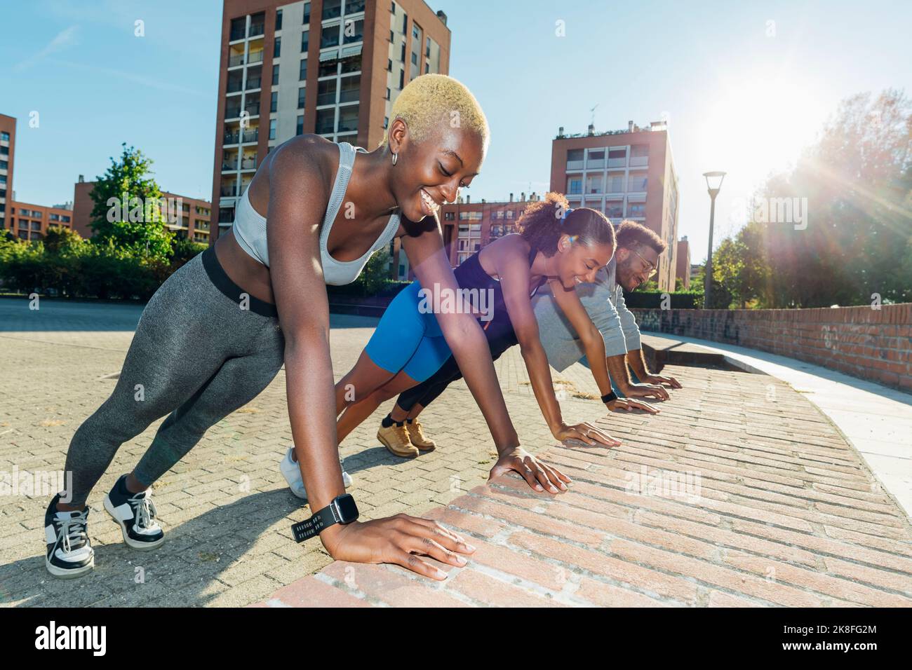 Smiling sports people doing push-ups on wall Stock Photo - Alamy