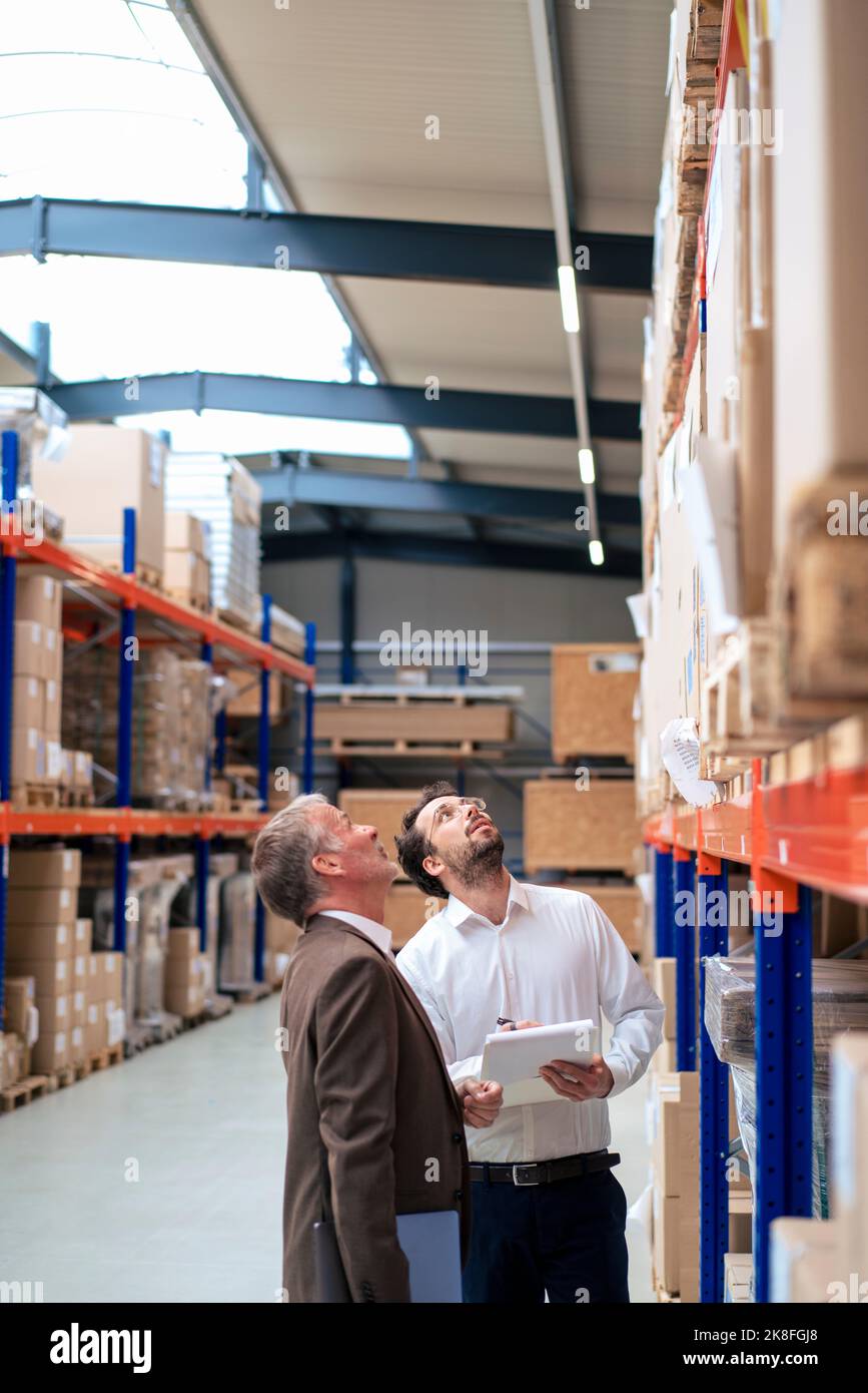 Senior businessman with colleague taking inventory at warehouse Stock ...