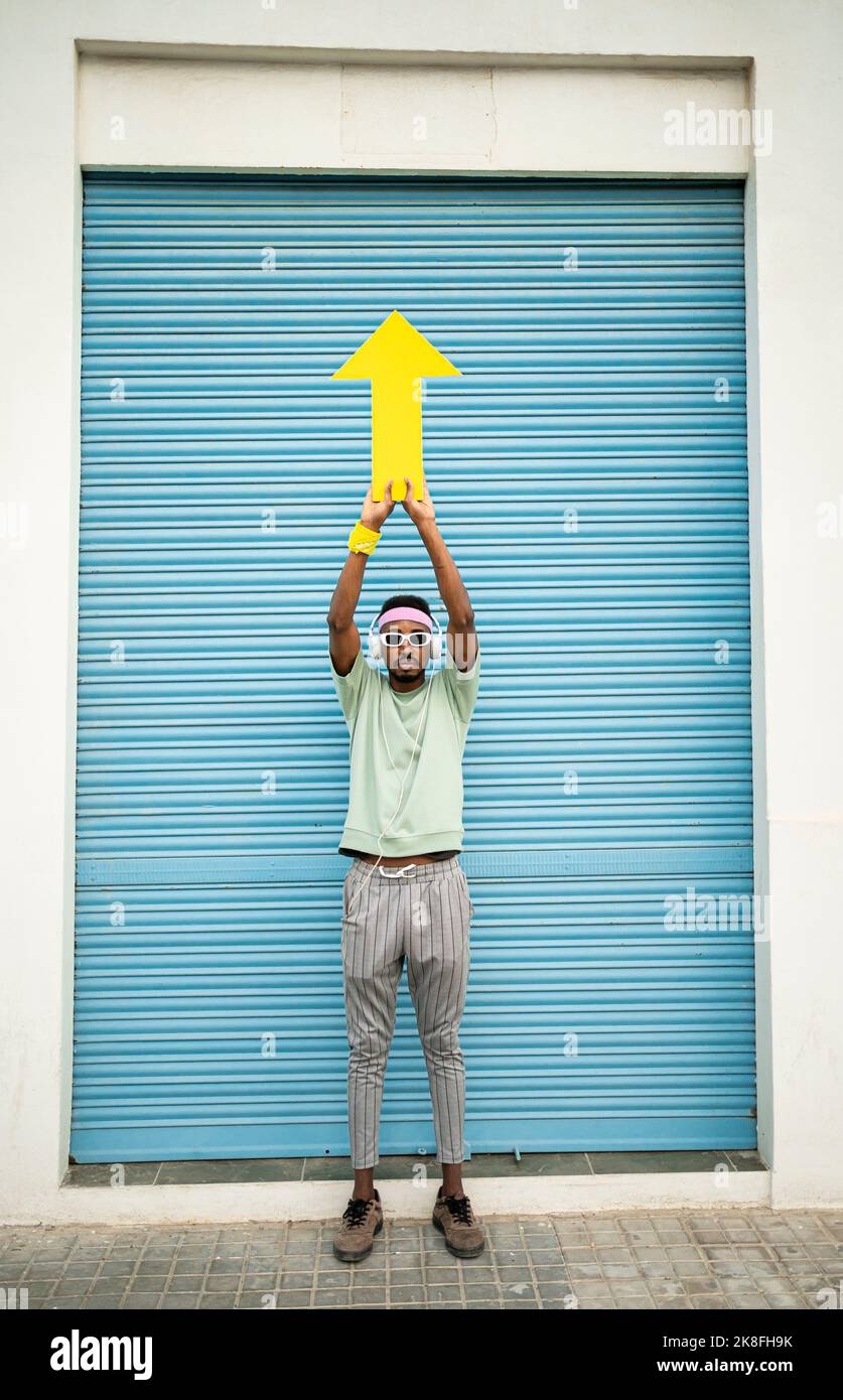 Man standing in front of shutter with yellow arrow sign Stock Photo - Alamy