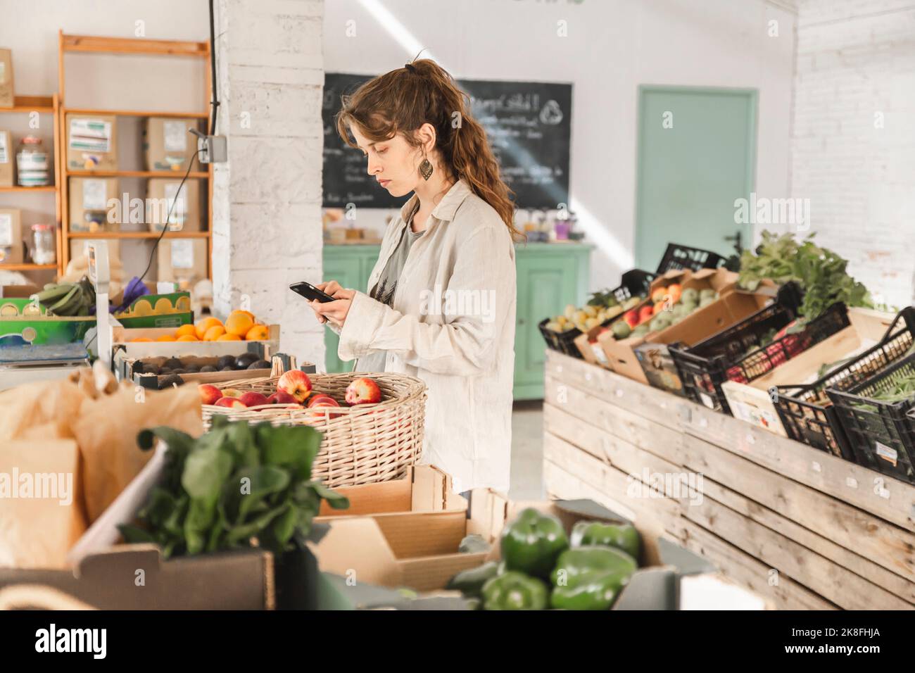 Customer using smart phone standing in vegetable store Stock Photo - Alamy