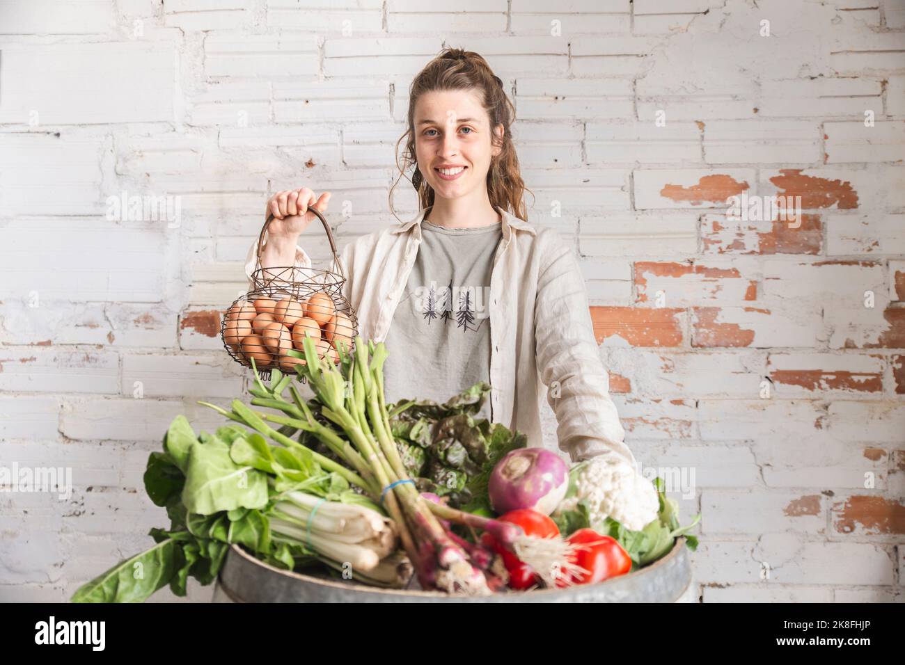 Smiling owner with eggs and vegetables in front of brick wall Stock ...