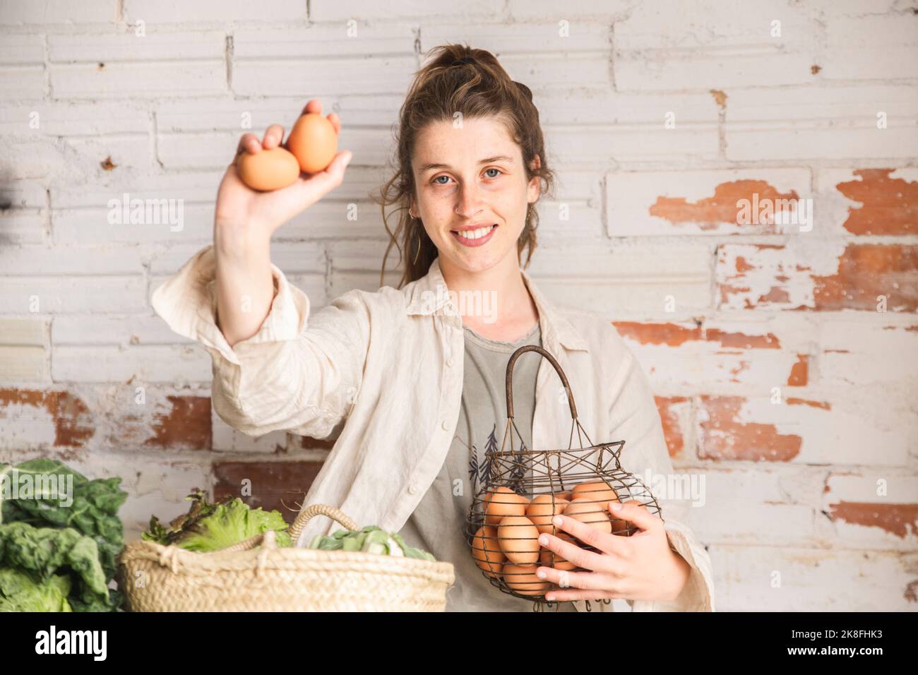Smiling grocer showing eggs in front of brick wall Stock Photo - Alamy