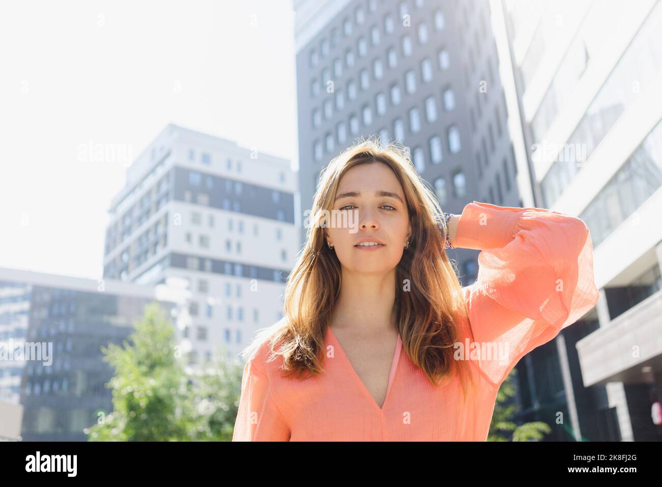 Beautiful woman with hand behind head in front of modern building Stock ...