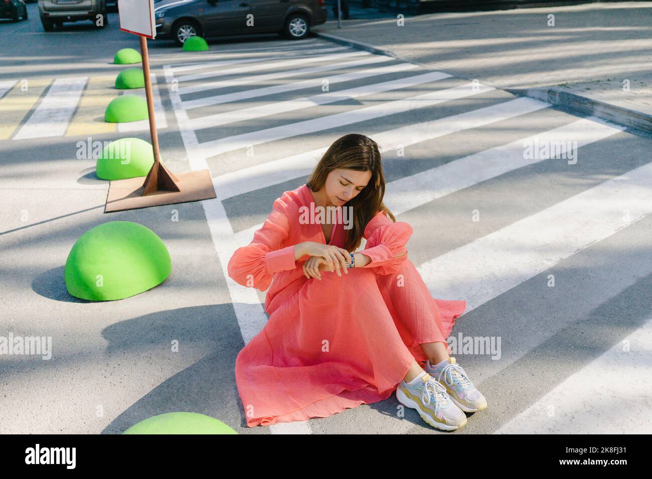 Woman checking time in watch sitting on road Stock Photo - Alamy