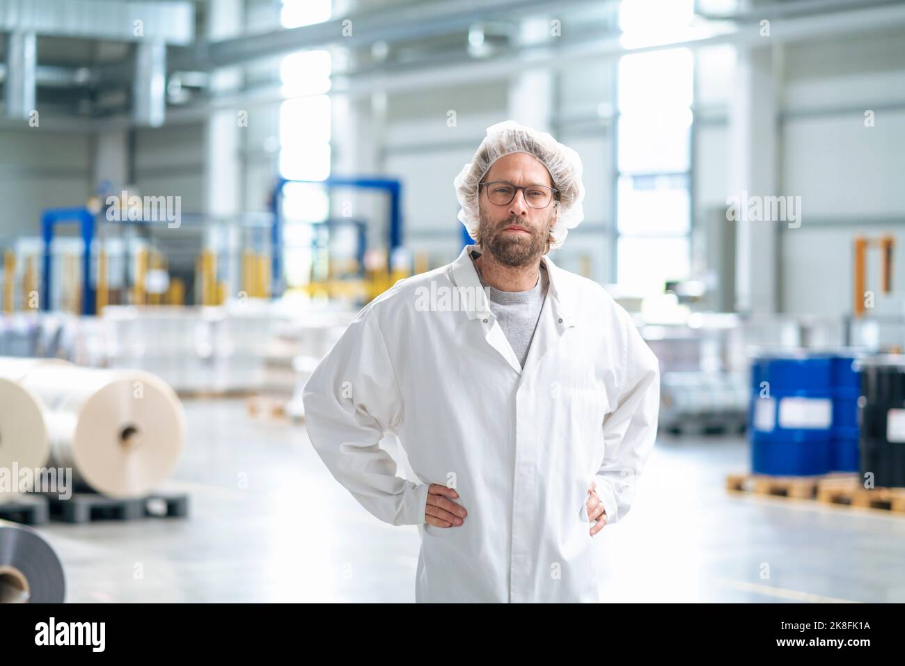 Man wearing lab coat standing with hands on hip in industry Stock Photo ...