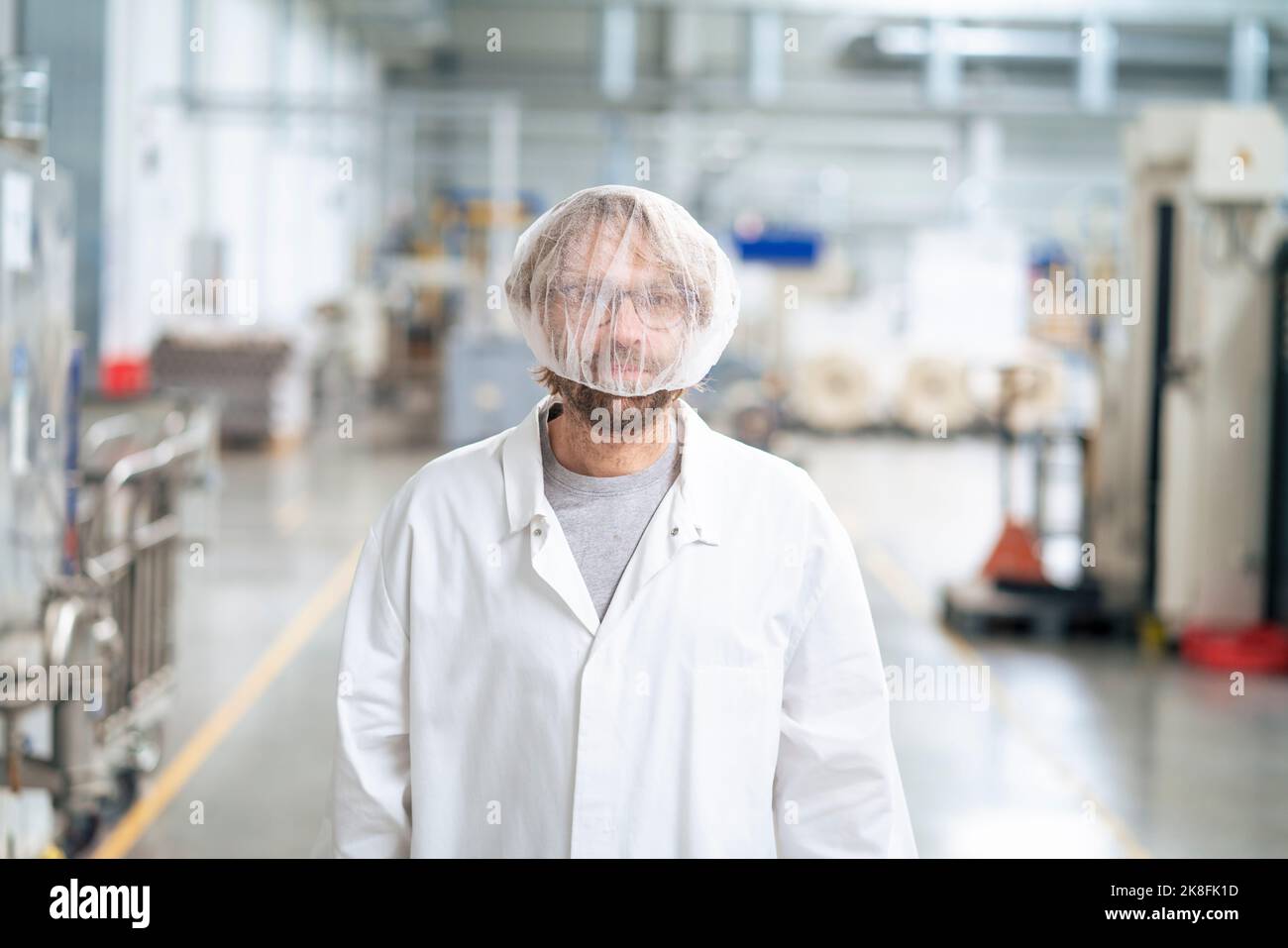 Man wearing lab coat and disposable cap standing in industry Stock ...