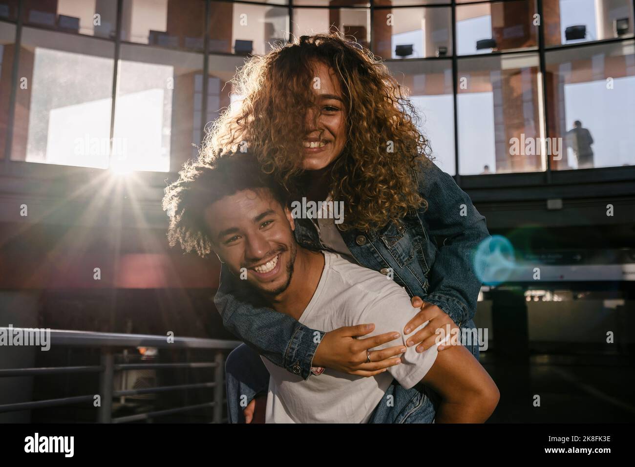 Happy young man carrying friend piggy back at railroad station Stock ... Happy young man carrying friend piggy back at railroad station Stock ...
