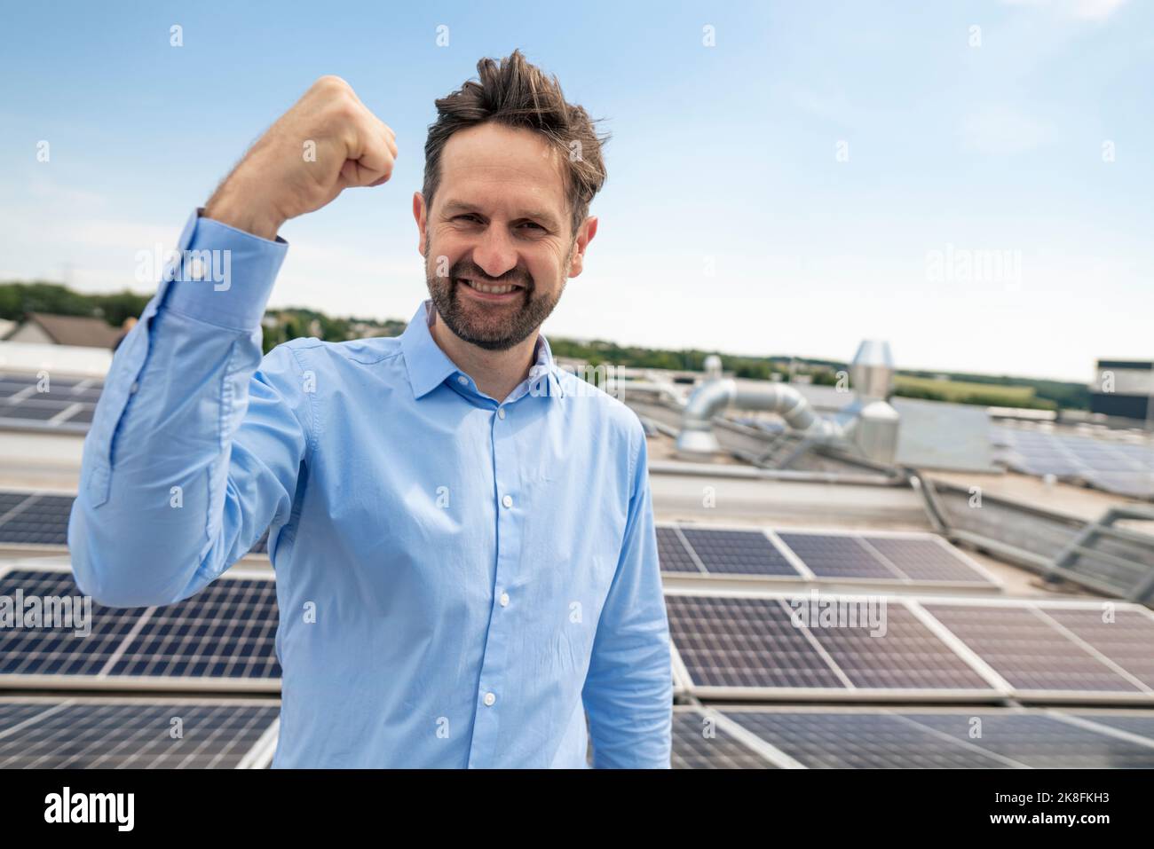 Smiling businessman gesturing fist in front of solar panels Stock Photo ...