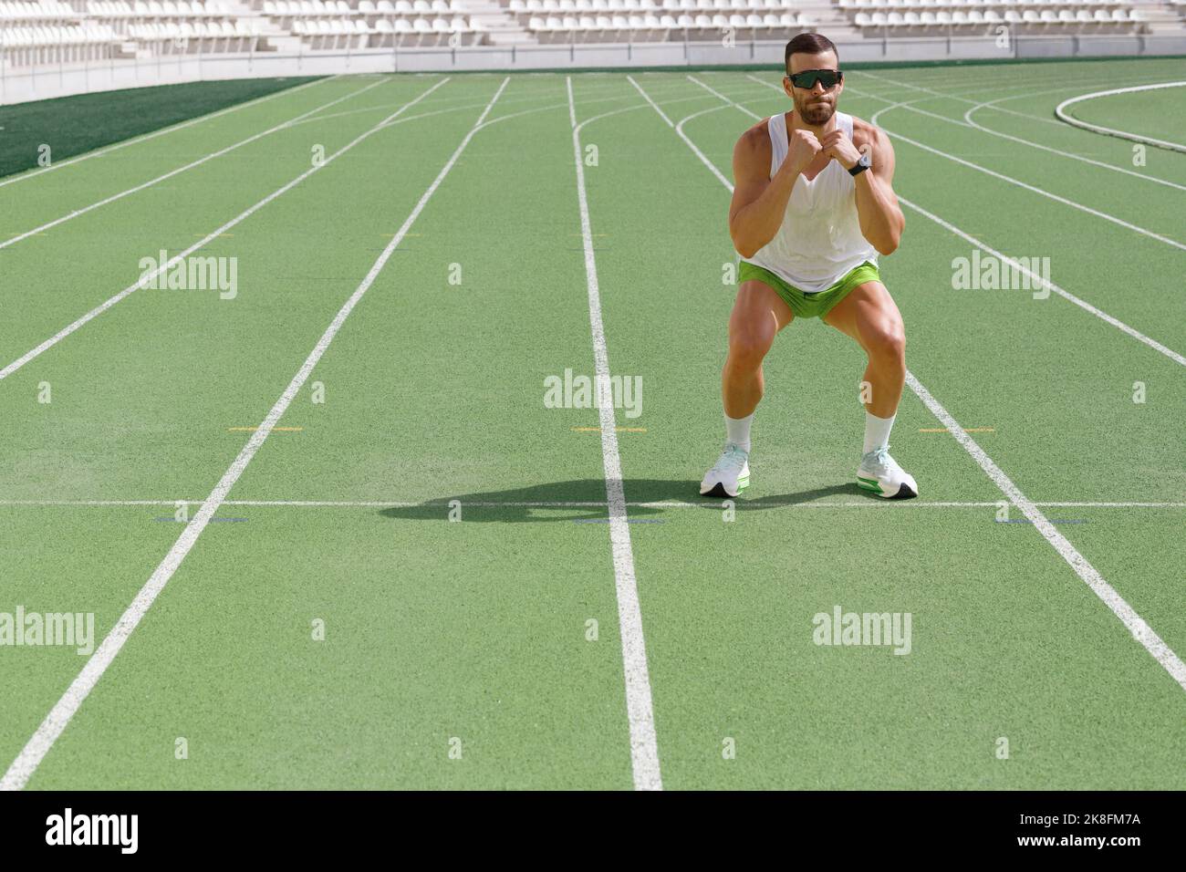 Athlete doing squat exercise on running track Stock Photo - Alamy