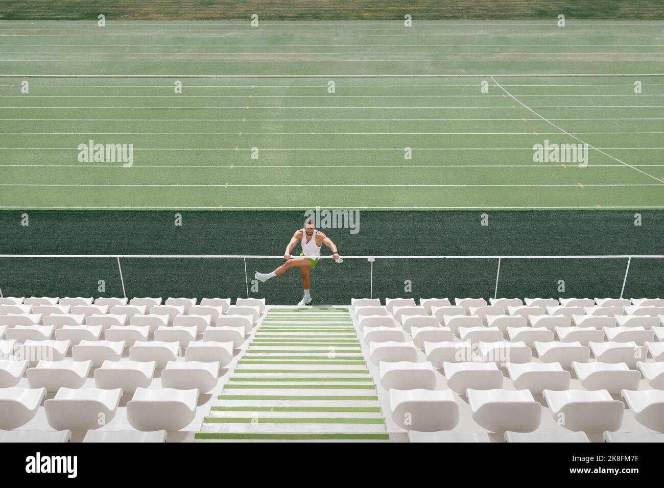 Sportsman doing warm up exercise on railing at stadium Stock Photo - Alamy
