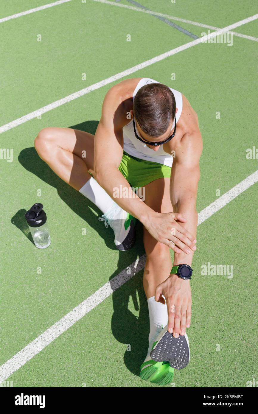Athlete doing stretching exercise sitting on ground Stock Photo - Alamy