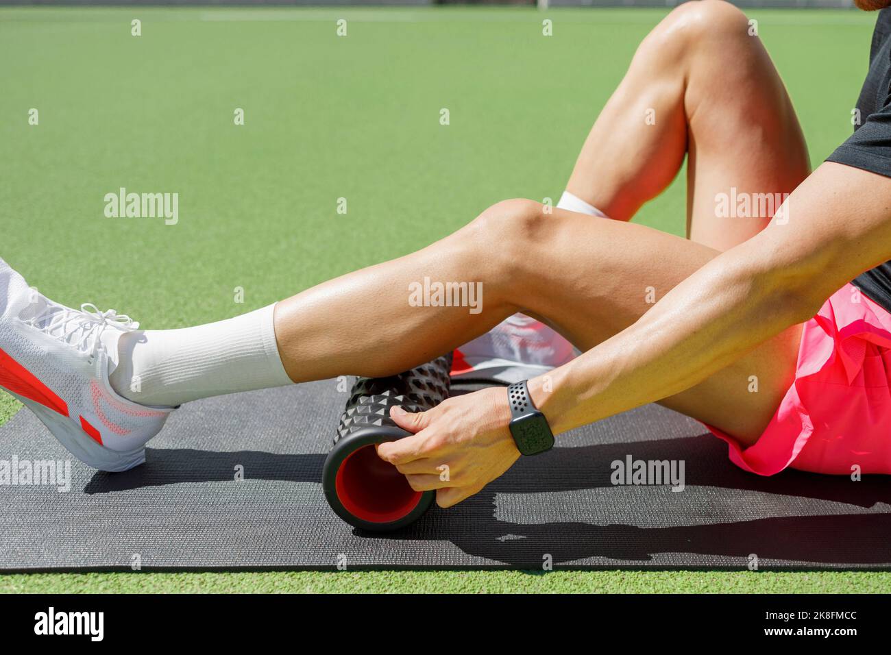 Athlete using foam roller for stretching muscles on sports field Stock ...