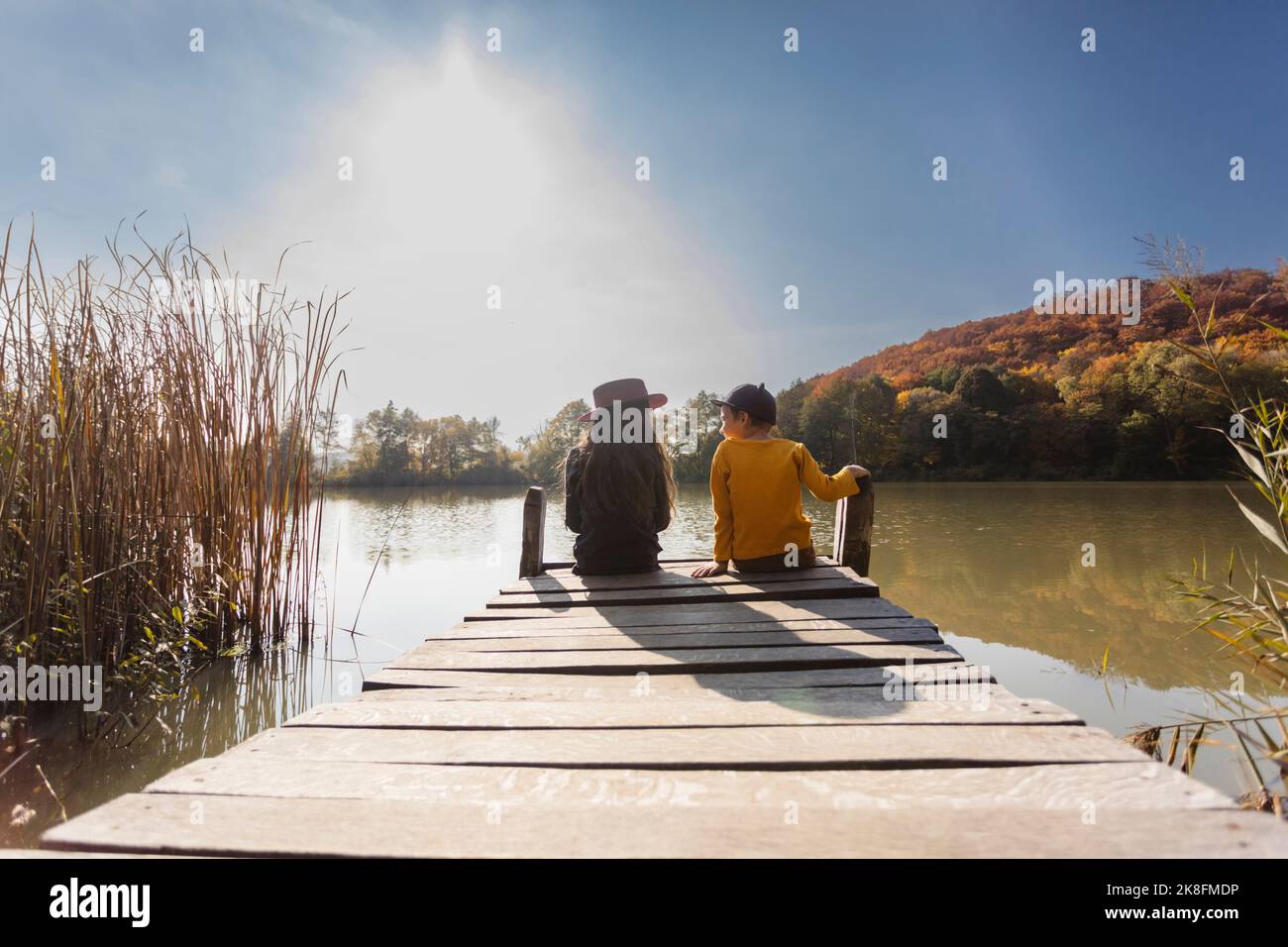 Boy and girl sitting on jetty on sunny day Stock Photo - Alamy