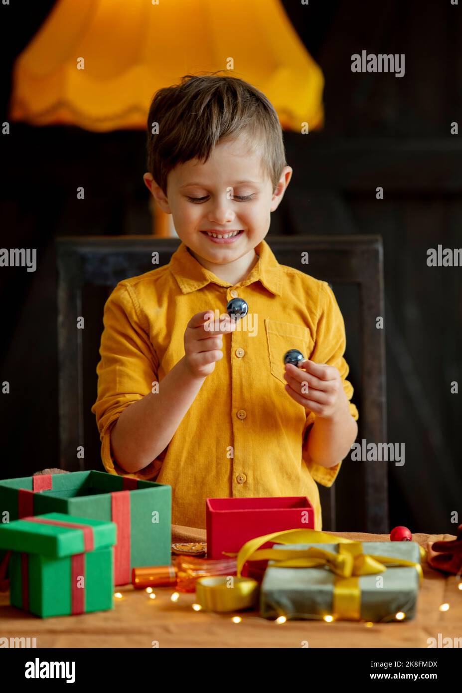 Smiling boy with Christmas baubles and gifts at table Stock Photo - Alamy