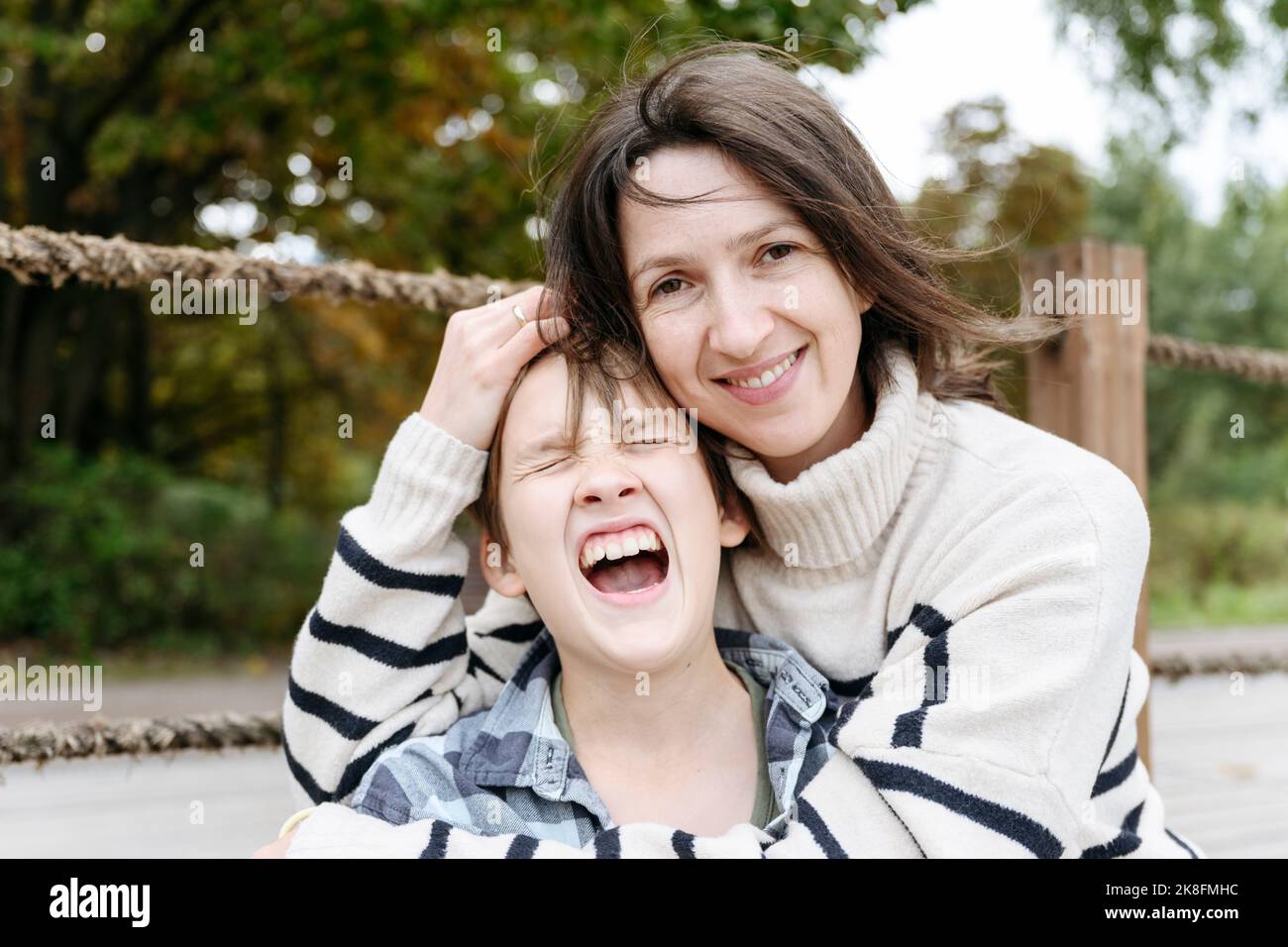 Smiling mother embracing son screaming in park Stock Photo - Alamy