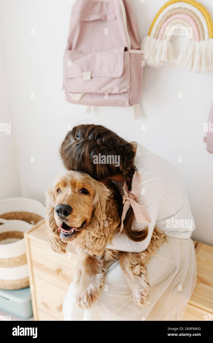 Girl embracing dog sitting on cabinet Stock Photo - Alamy