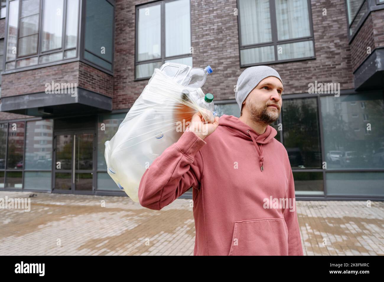 Man carrying garbage bag on shoulder in front of building Stock Photo ...