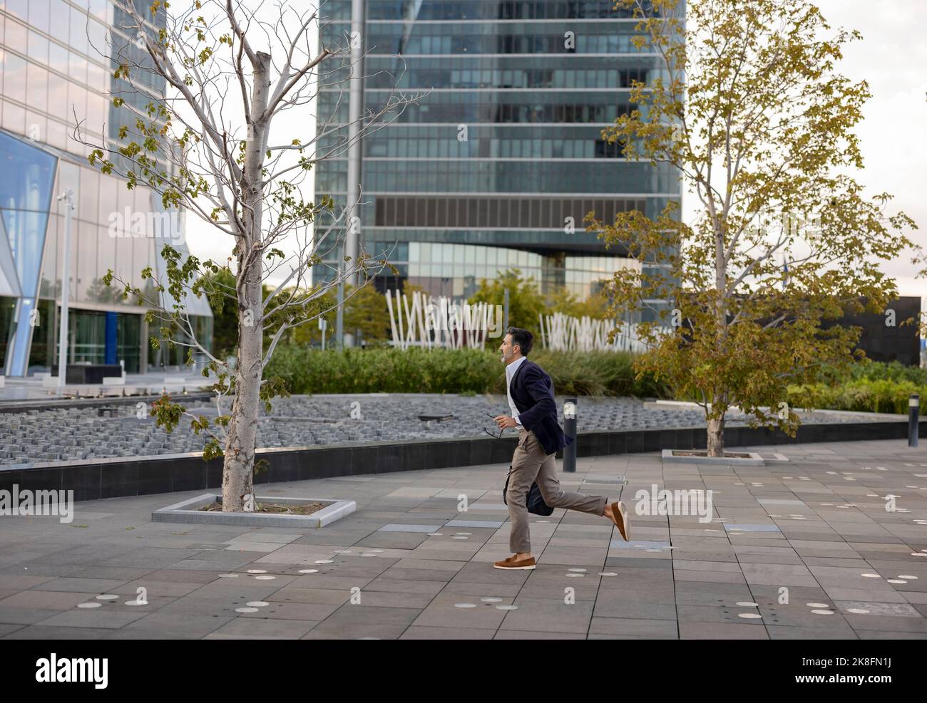 Businessman running on footpath in front of office building Stock Photo ...