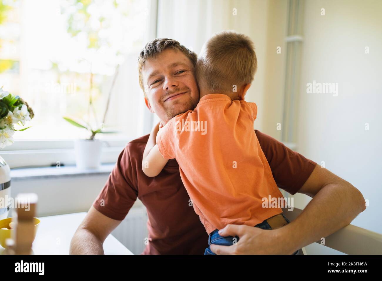 Boy embracing smiling father at home Stock Photo - Alamy