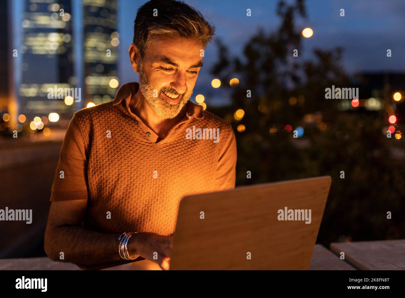 Happy businessman using laptop in city at night Stock Photo - Alamy