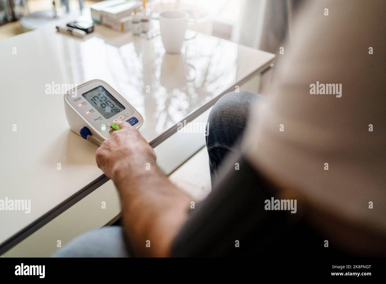 Man using blood pressure device on table at home Stock Photo - Alamy