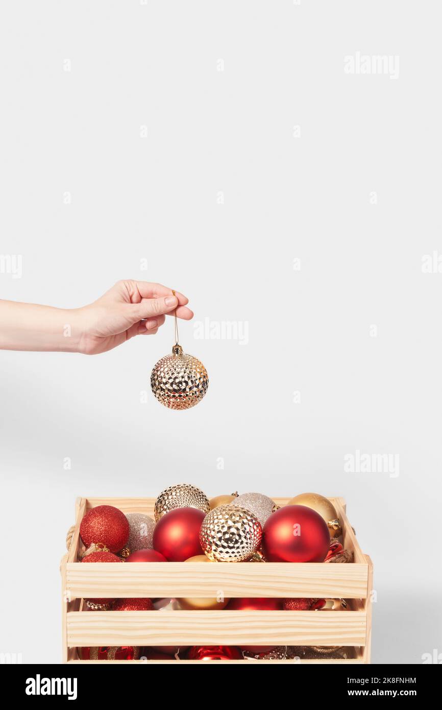 Woman's hand holding golden bauble over box with colorful balls against ...