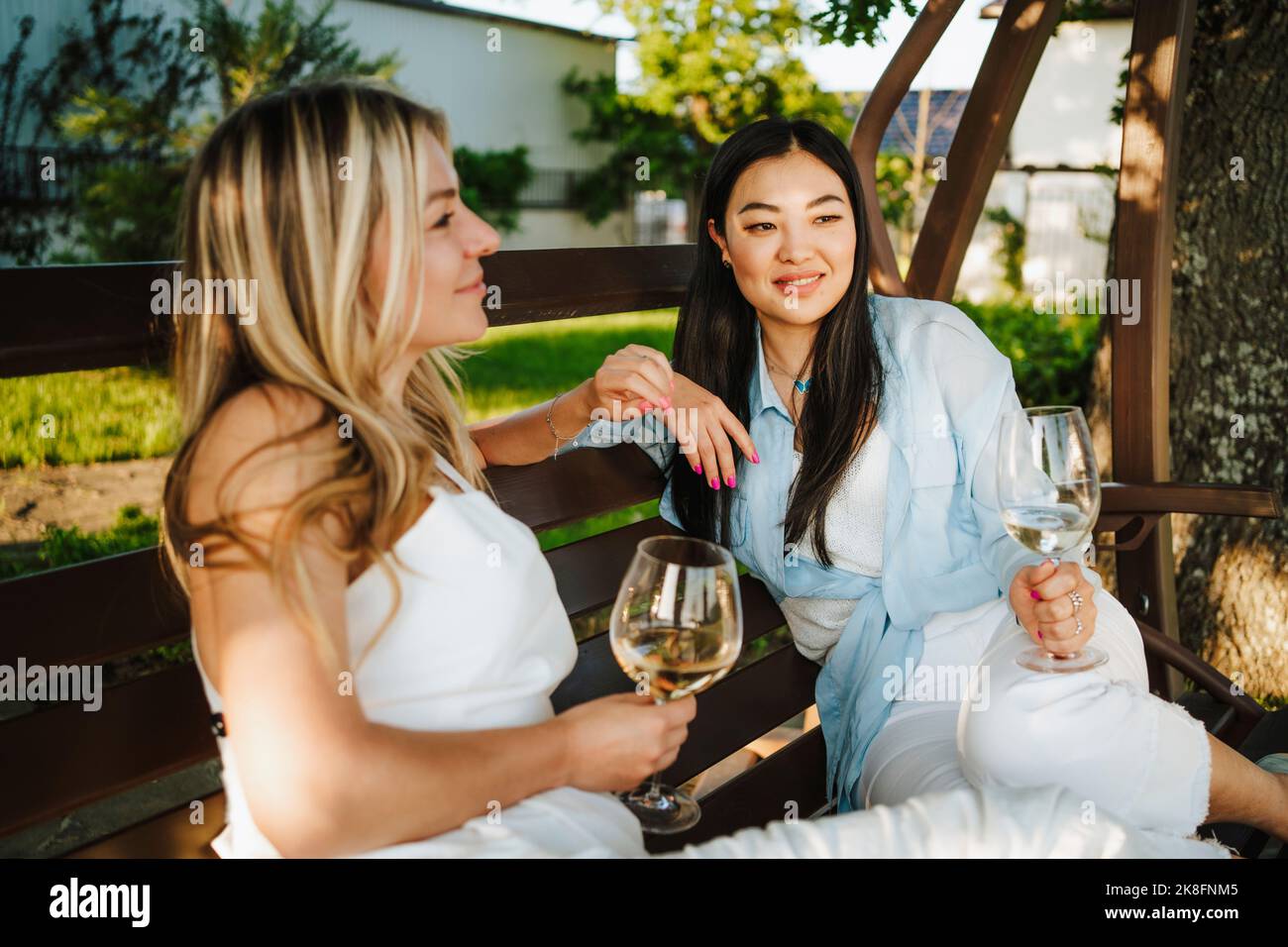 Women sitting on porch swing enjoying wine Stock Photo - Alamy