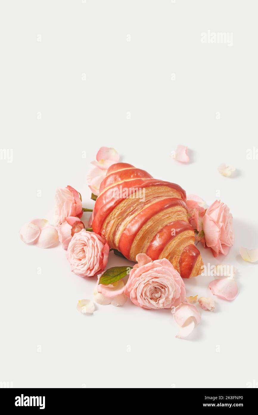 Pink rose petals around croissant on white background Stock Photo - Alamy