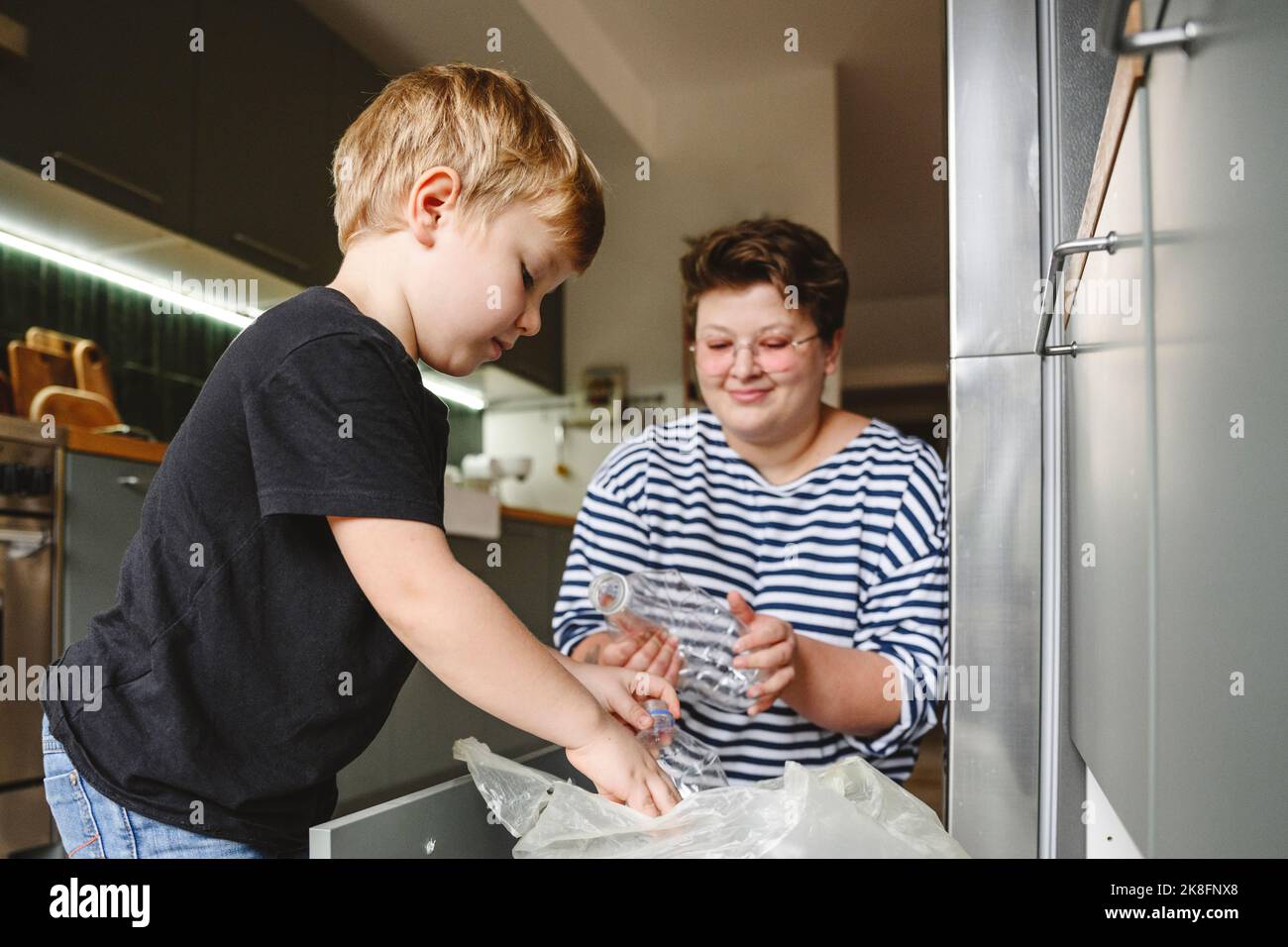 Mother and son sorting plastic garbage in kitchen at home Stock Photo ...