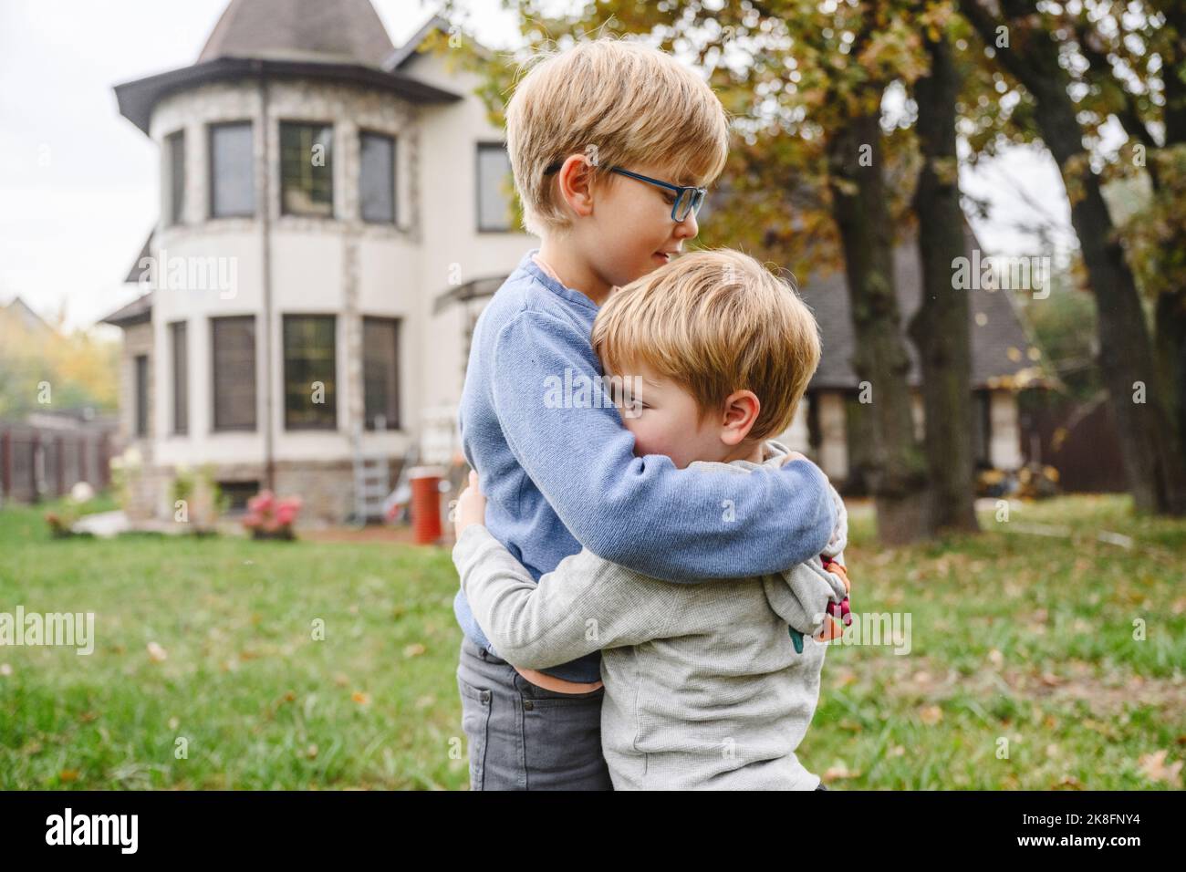 Siblings hugging each other in back yard Stock Photo - Alamy