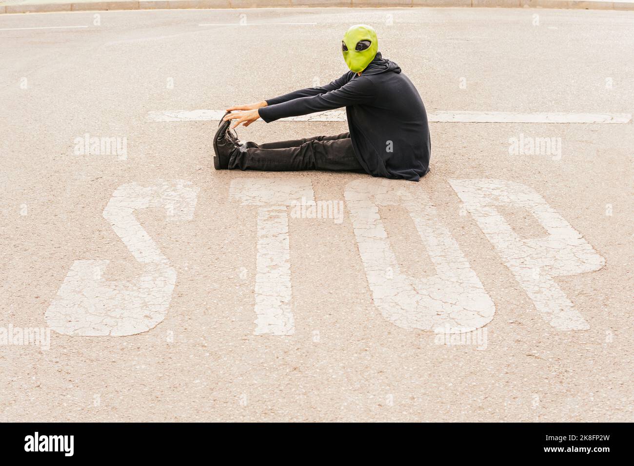 Man wearing alien mask sitting in front of STOP sign on road Stock ...
