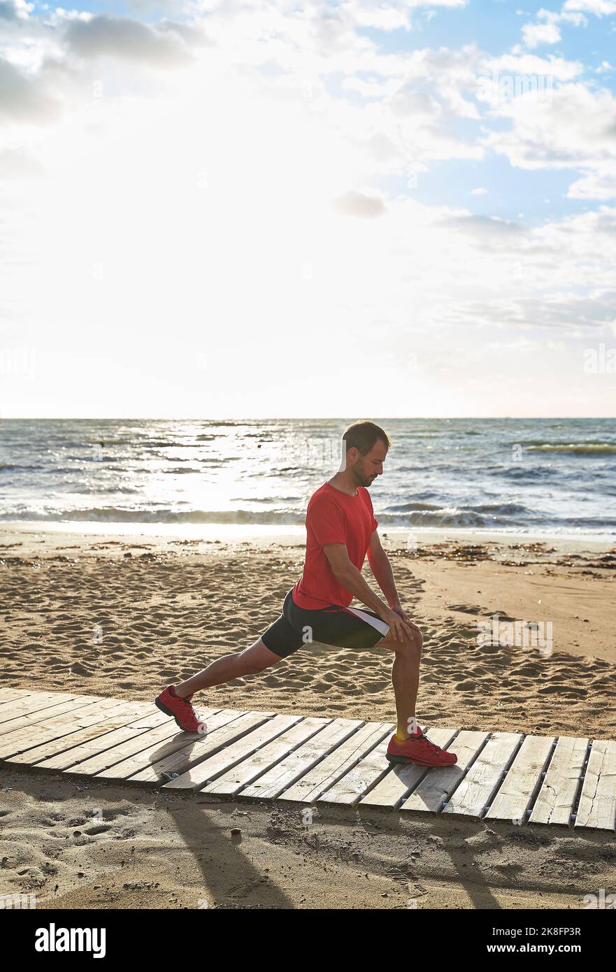 Man doing stretching exercise on boardwalk at beach Stock Photo - Alamy