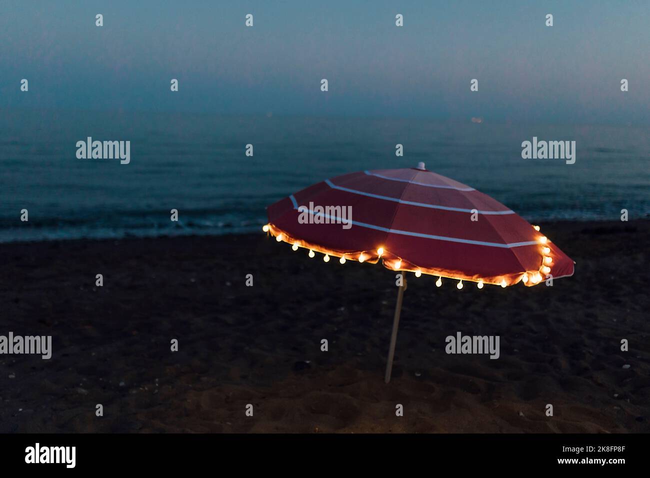 Illuminated string light on pink umbrella at beach Stock Photo - Alamy