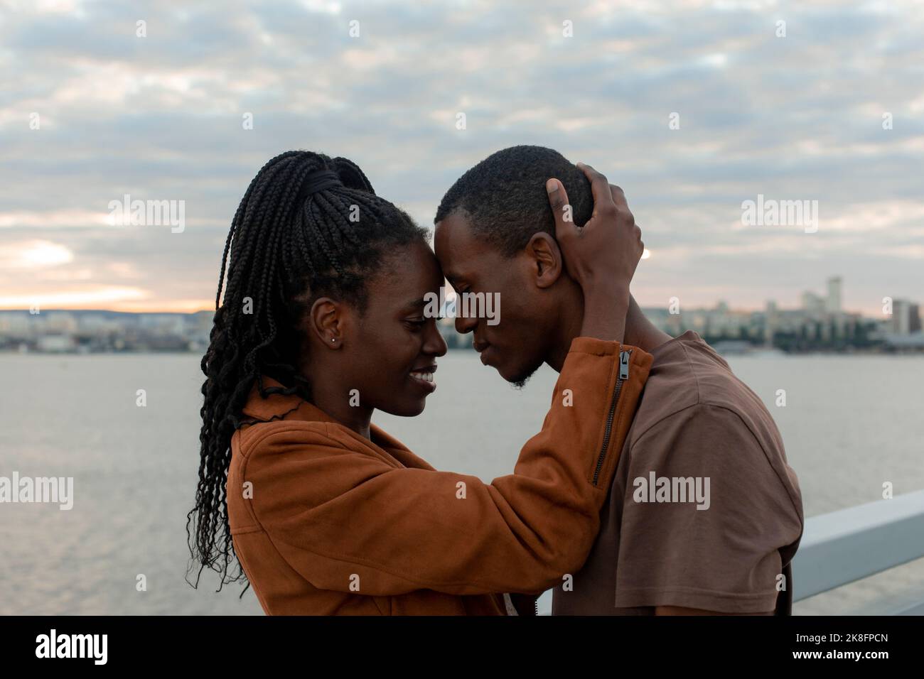 Romantic couple head to head by railing in front of river Stock Photo ...