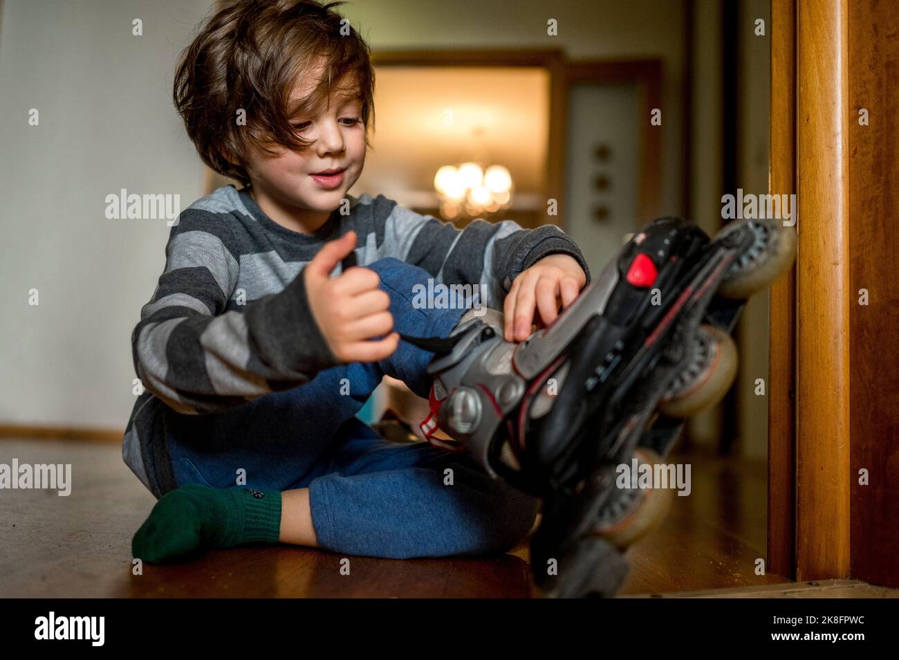 Cute boy wearing roller skates sitting on floor at home Stock Photo - Alamy