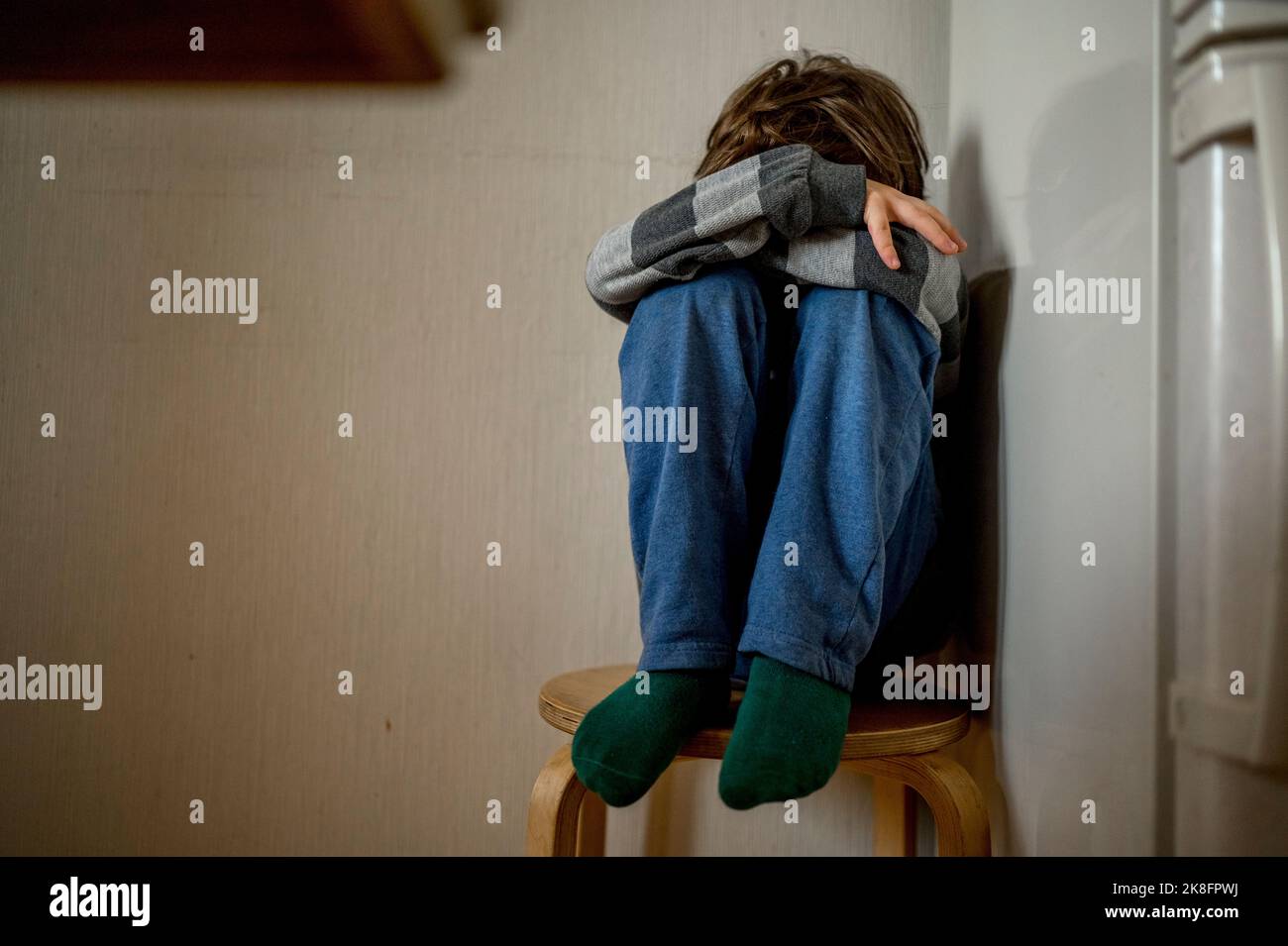 Depressed boy on stool at home Stock Photo - Alamy
