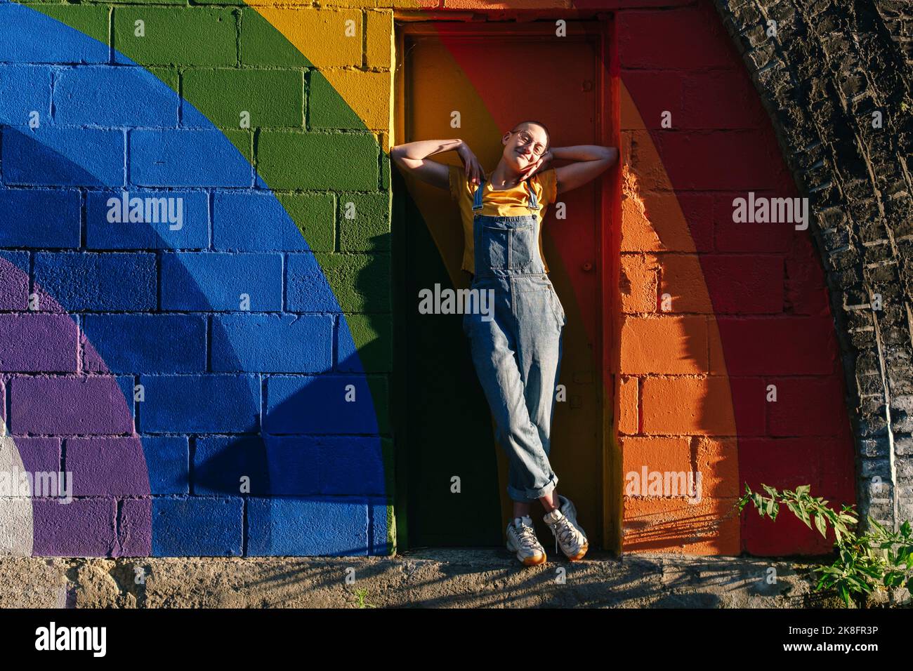 Smiling non-binary person standing in front of door Stock Photo - Alamy